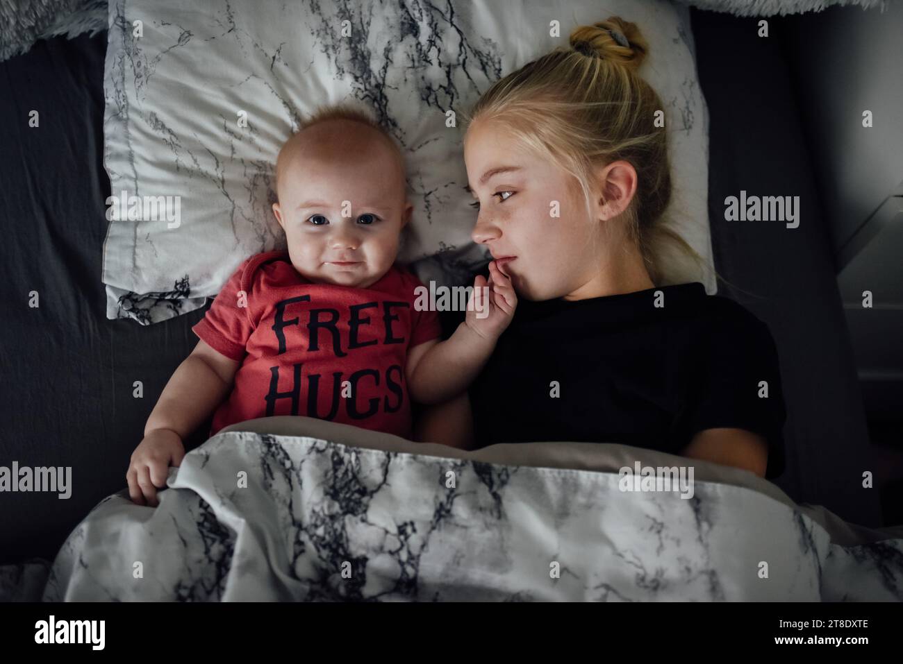 Overhead view of baby laying in bed looking at camera while cudd Stock ...