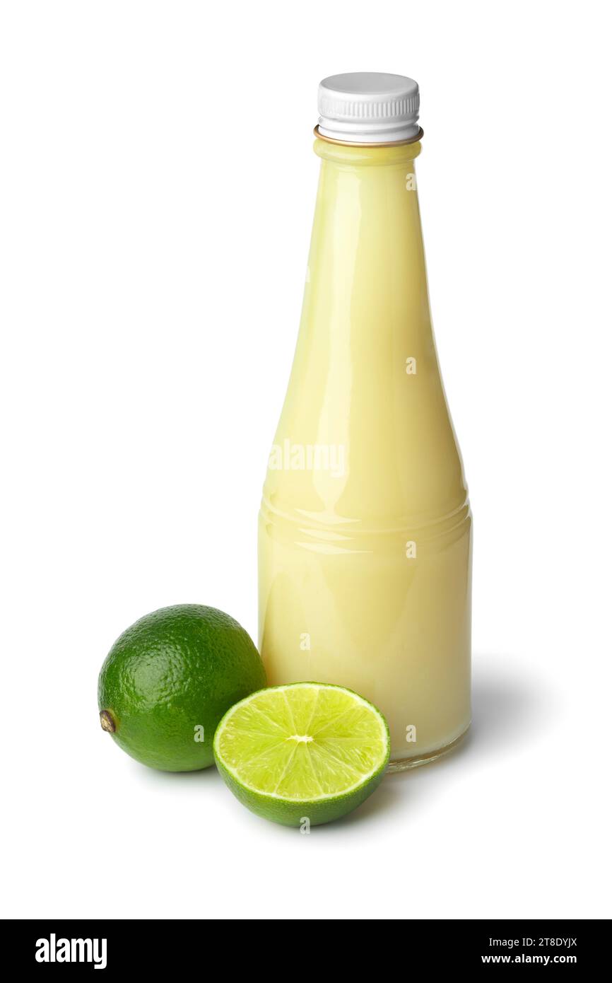 Glass bottle with lime juice and green lime in front close up isolated ...