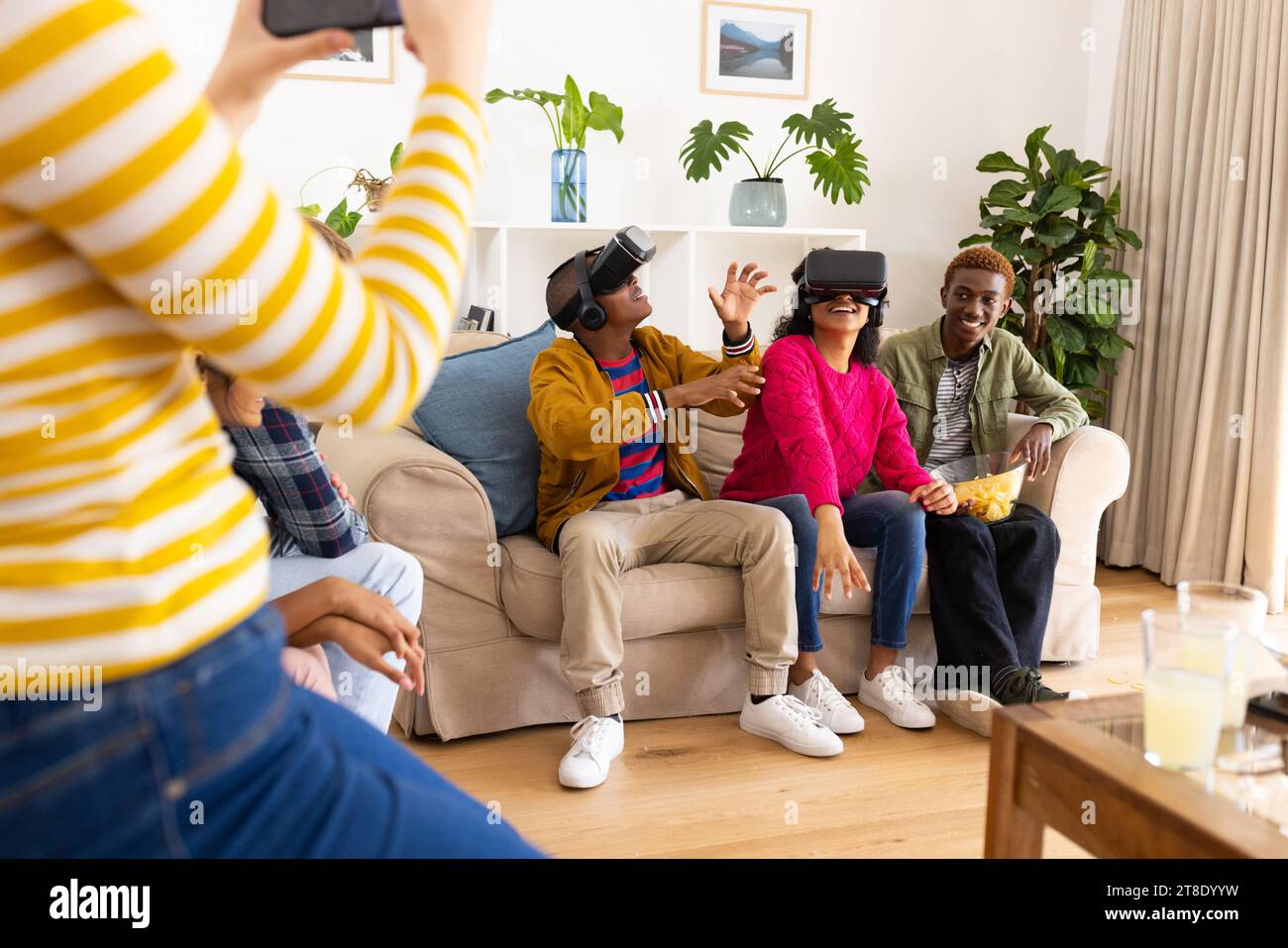 Happy diverse group of teenage friends with snacks using vr headsets ...