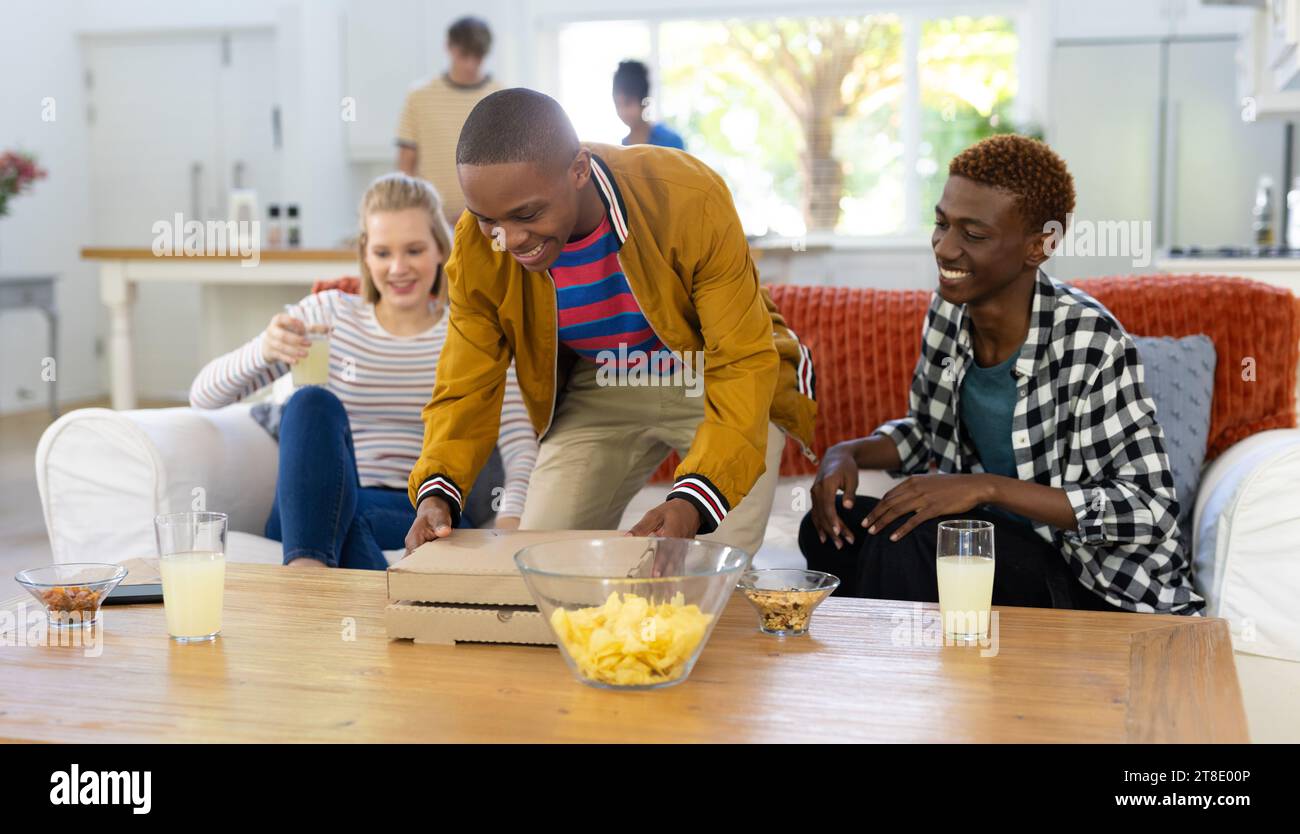 Happy diverse group of teenage friends with snacks and drinks eating ...