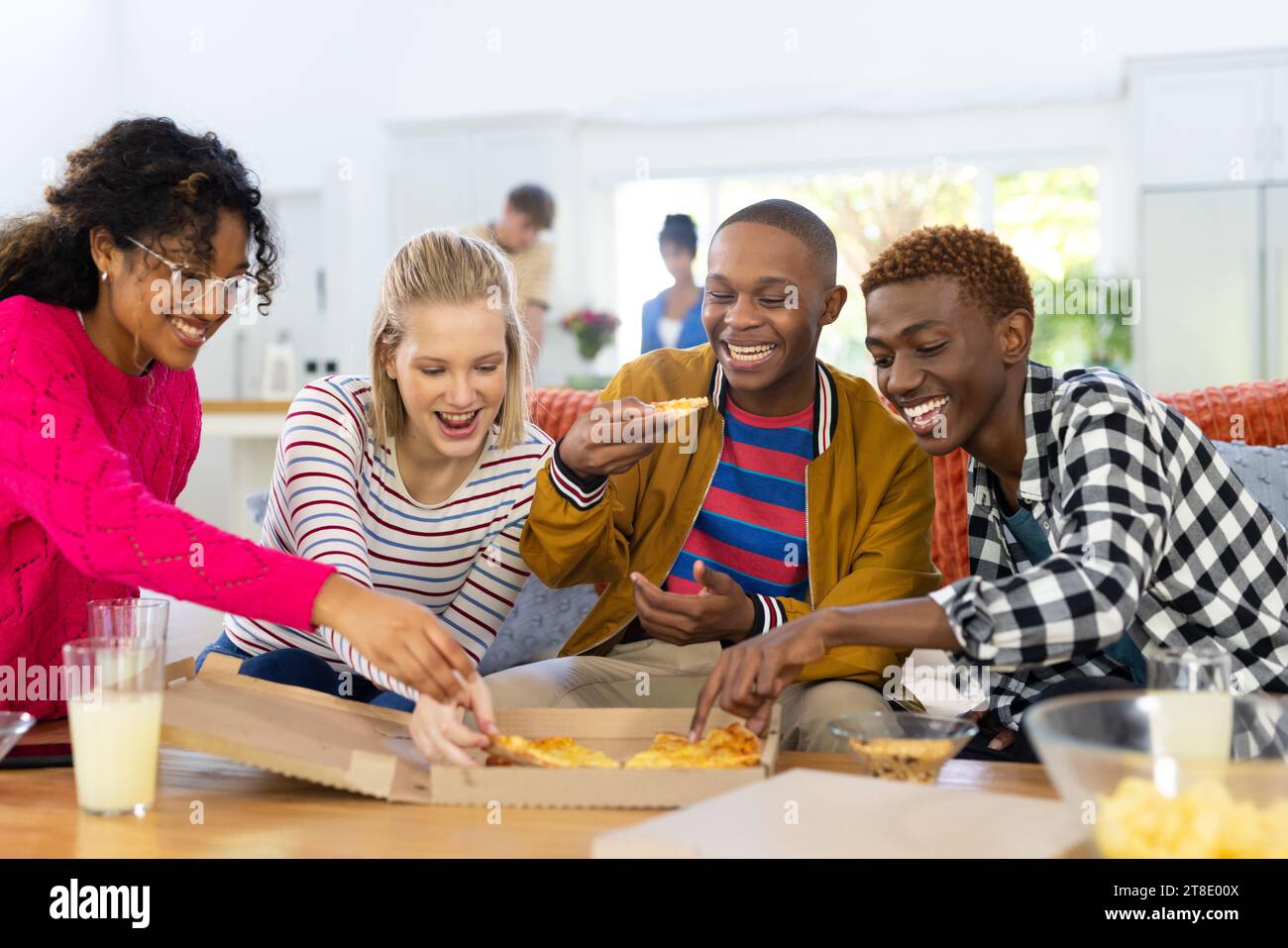 Happy diverse group of teenage friends with snacks and drinks eating ...