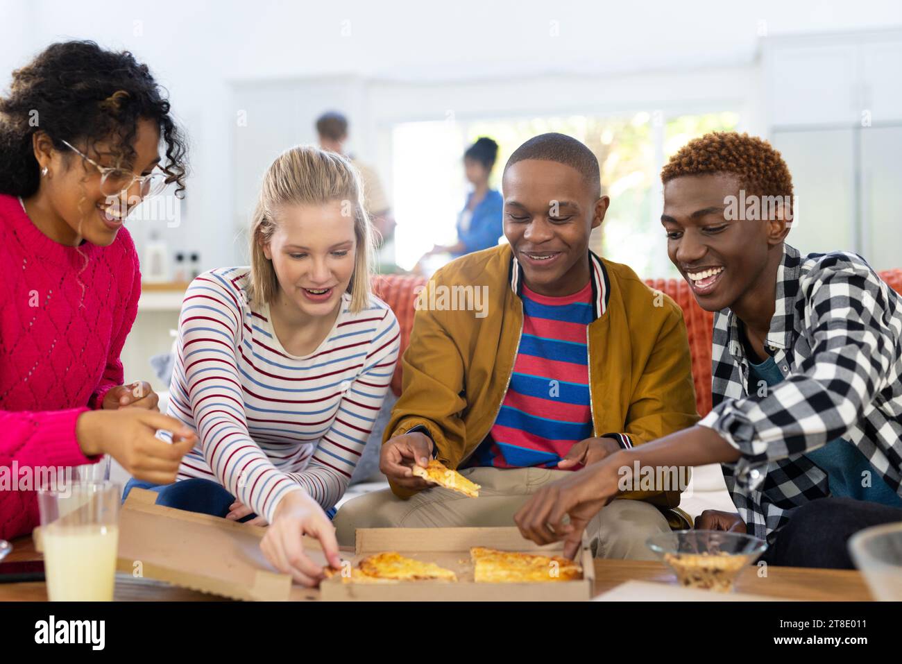 Happy diverse group of teenage friends with snacks and drinks eating ...