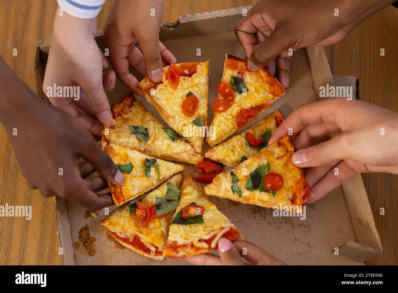 Diverse group of teenage friends sharing pizza on table at home Stock ...