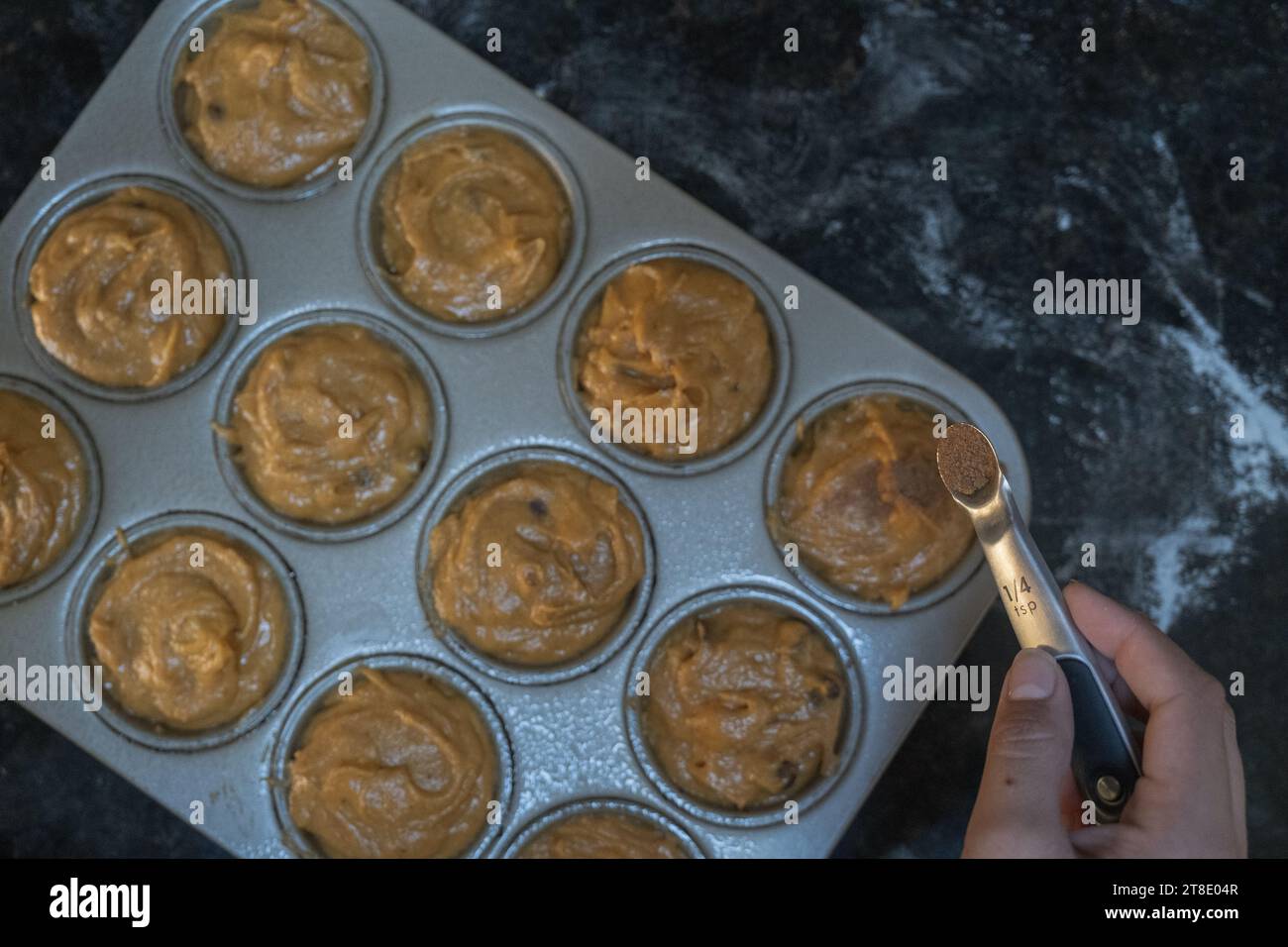 Overhead shot of hand adding spice topping on unbaked muffins Stock ...