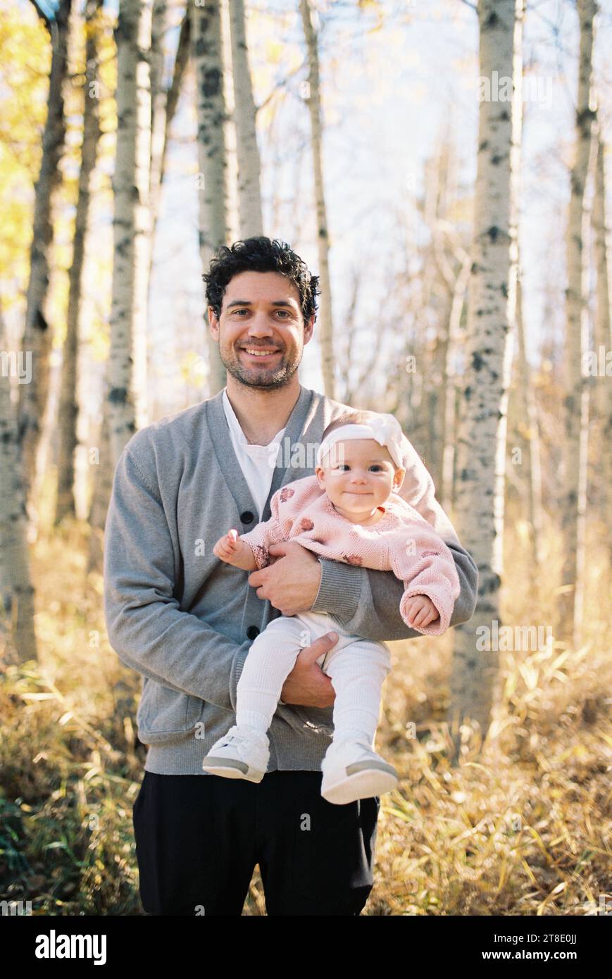 Young dad holding baby girl in front of fall leaves and forest Stock ...