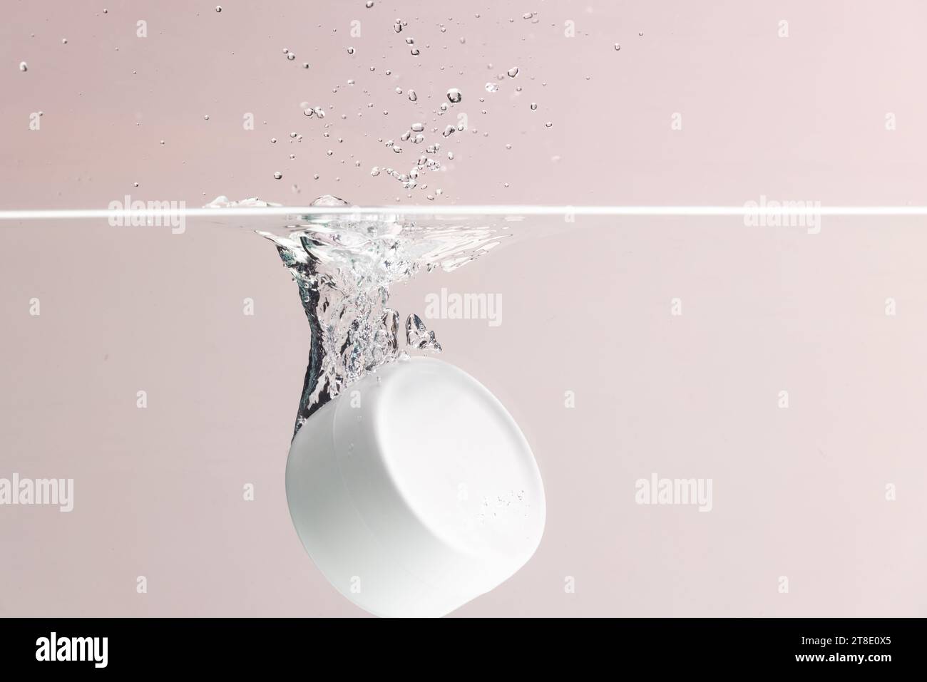 Beauty product tub falling into water with copy space background on ...