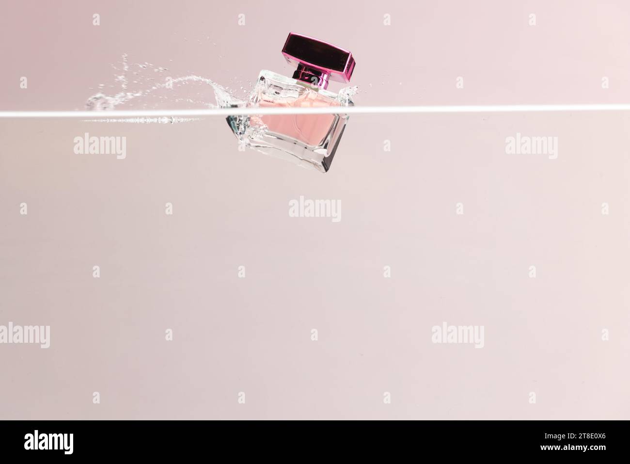 Beauty product perfume bottle falling into water with copy space ...