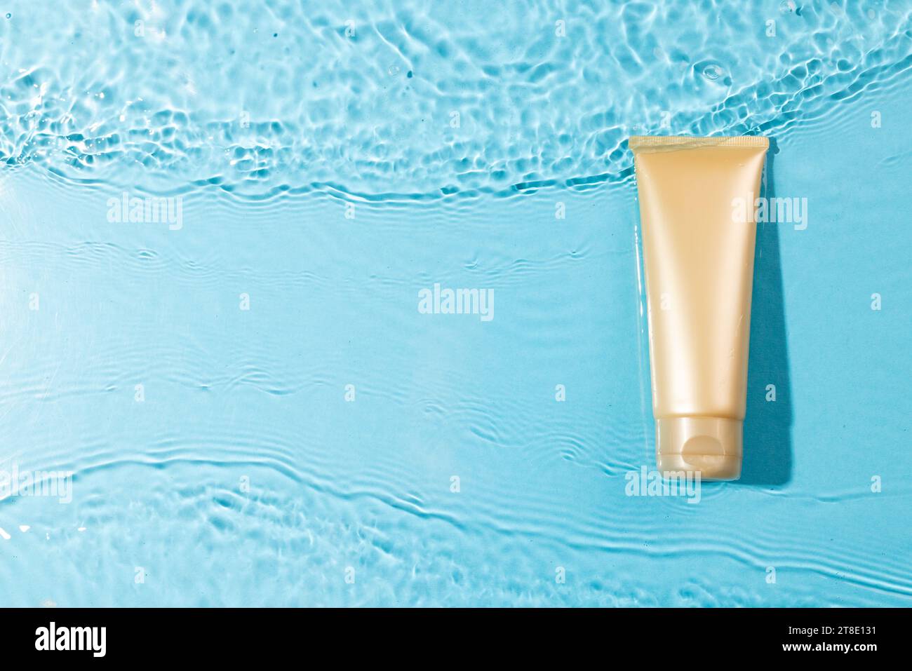Beauty product tube in water with copy space background on blue ...