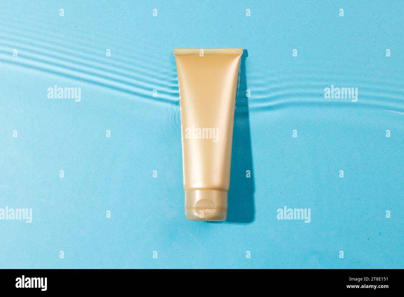 Beauty product tube in water with copy space background on blue ...
