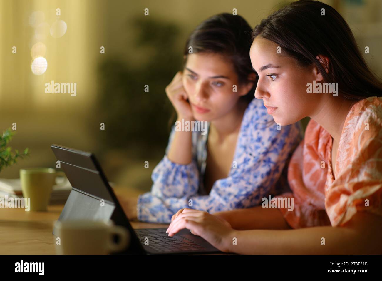 Two women checking tablet content in the night at home Stock Photo - Alamy