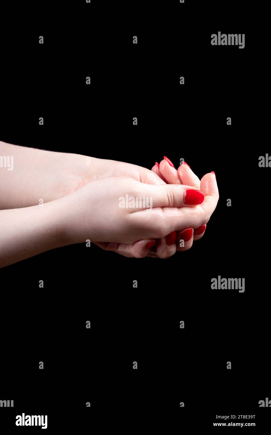 Female hands with red manicure rub hand sanitizer gel. Black background ...