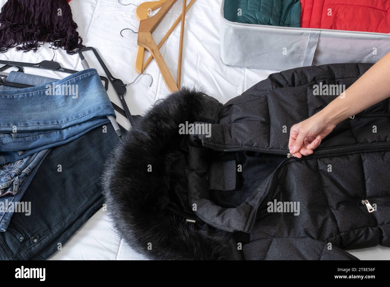 Horizontal photo, woman's hand closing the zipper of a black coat, on a ...