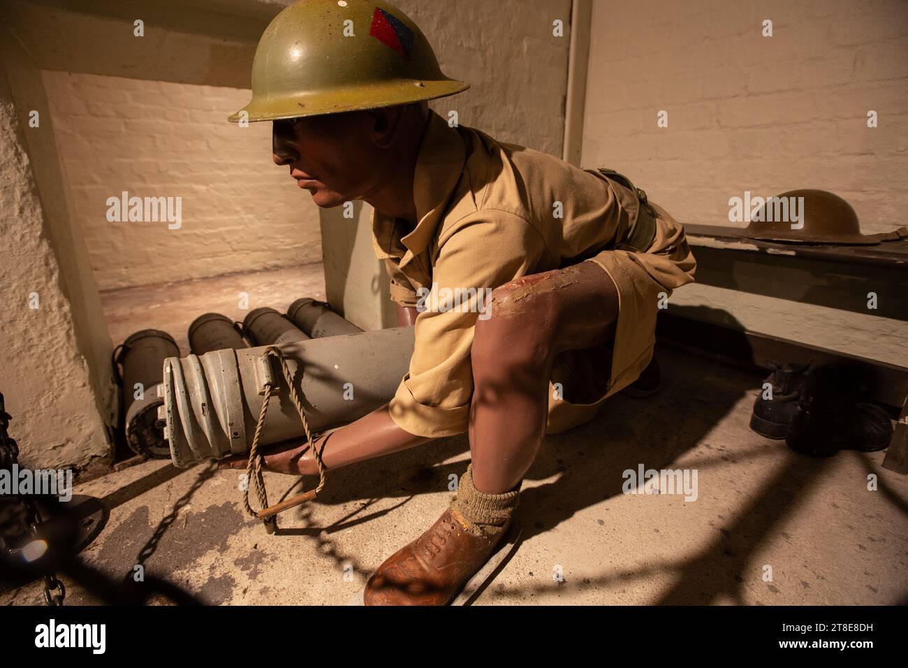 A British soldier is bending down to lift up gun shells for the 6-inch ...