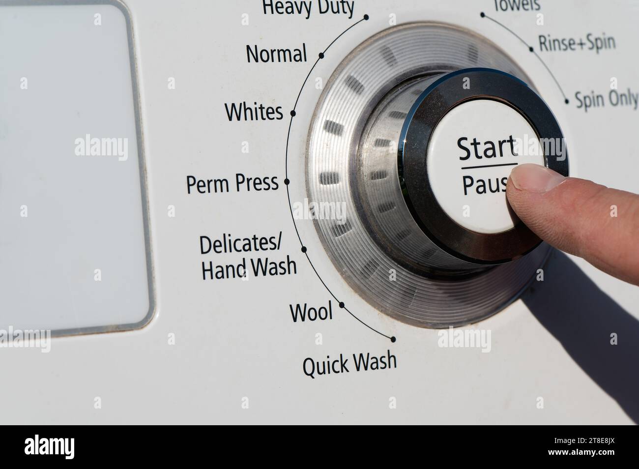 A finger pressing the start paude button on a washing machine Stock ...