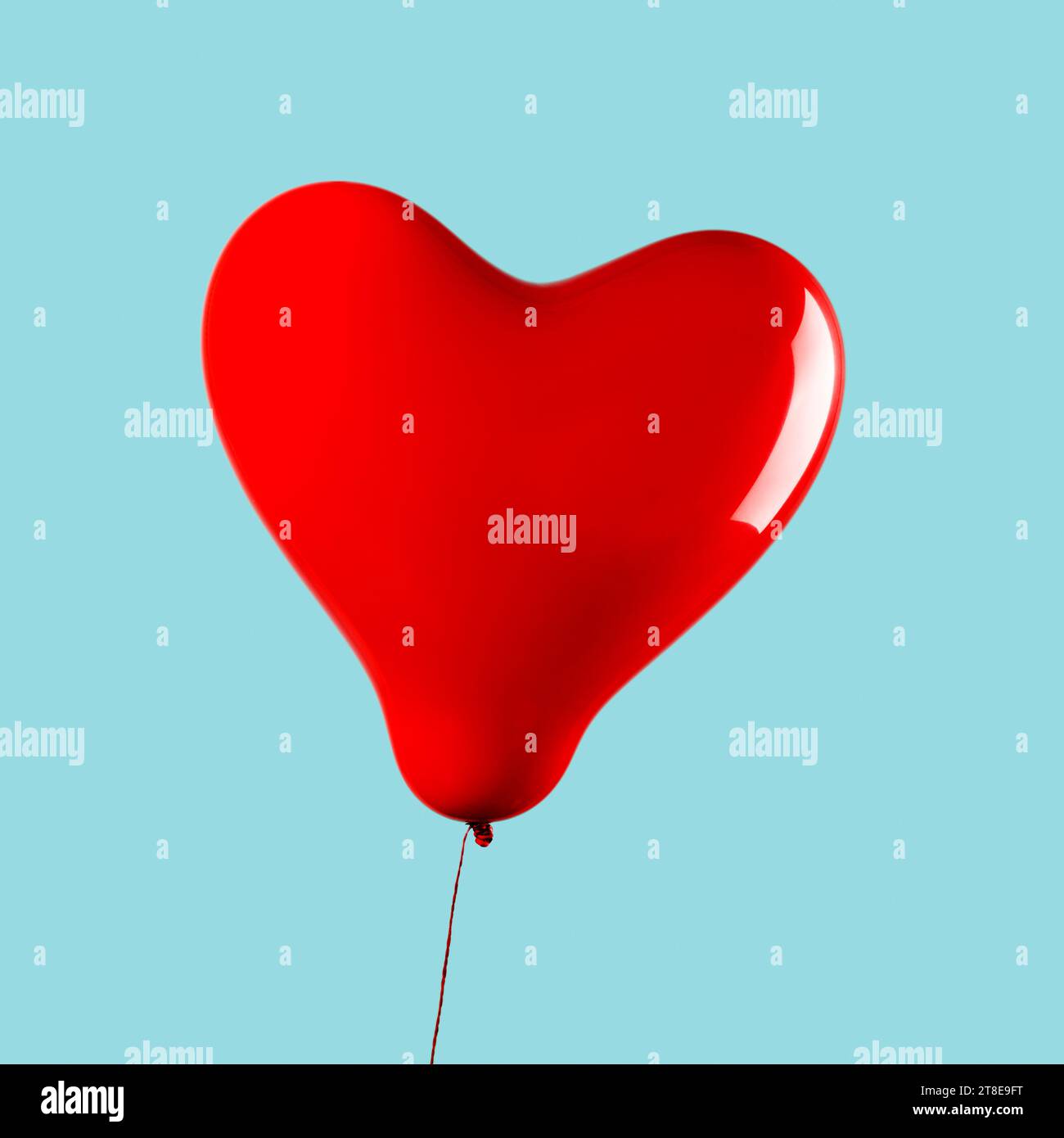 closeup of a red rubber heart-shaped balloon tied with a red string on ...