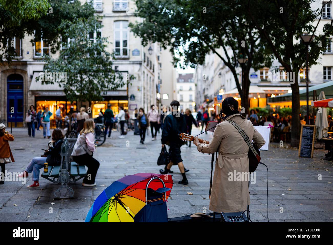 woman playing a guitar in a public square in paris france with a ...