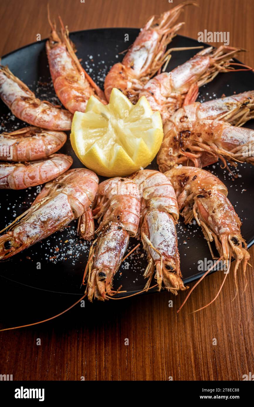 Vertical photo detail of grilled prawns served with lemon and salt ...