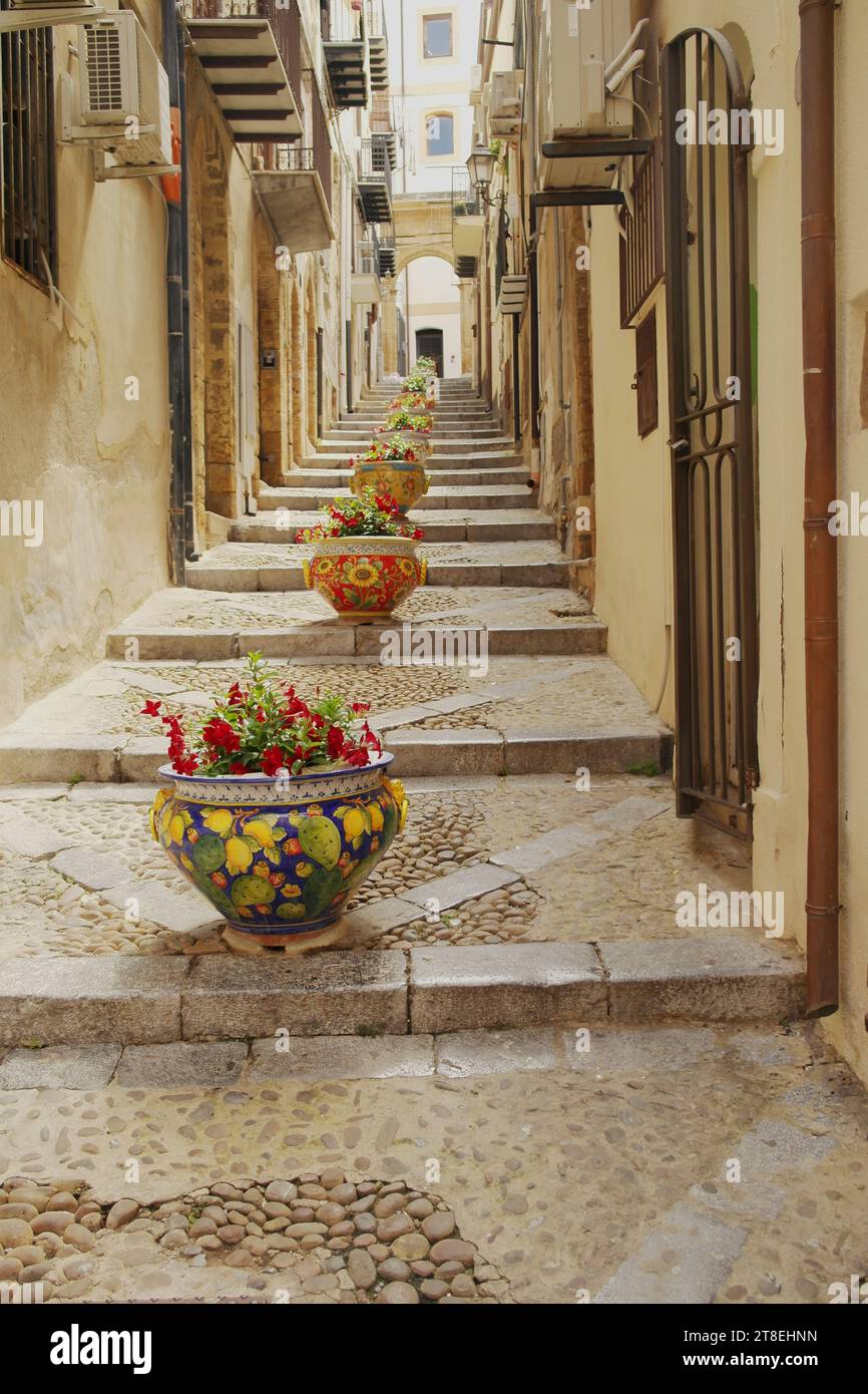 View of an alley with steps and colorful flower pots in Cefalu, Sicily ...