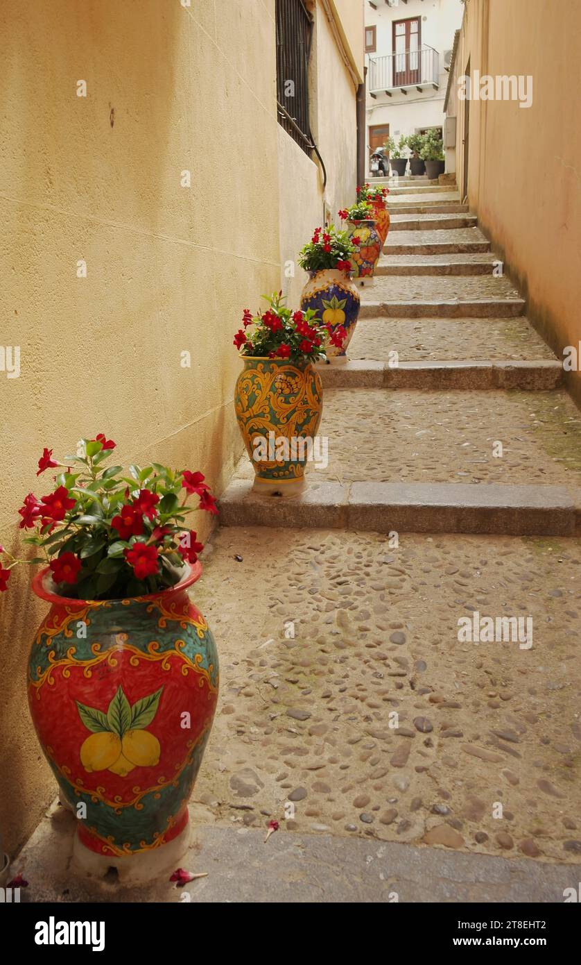 View of an alley with steps and colorful flower pots in Cefalu, Sicily ...