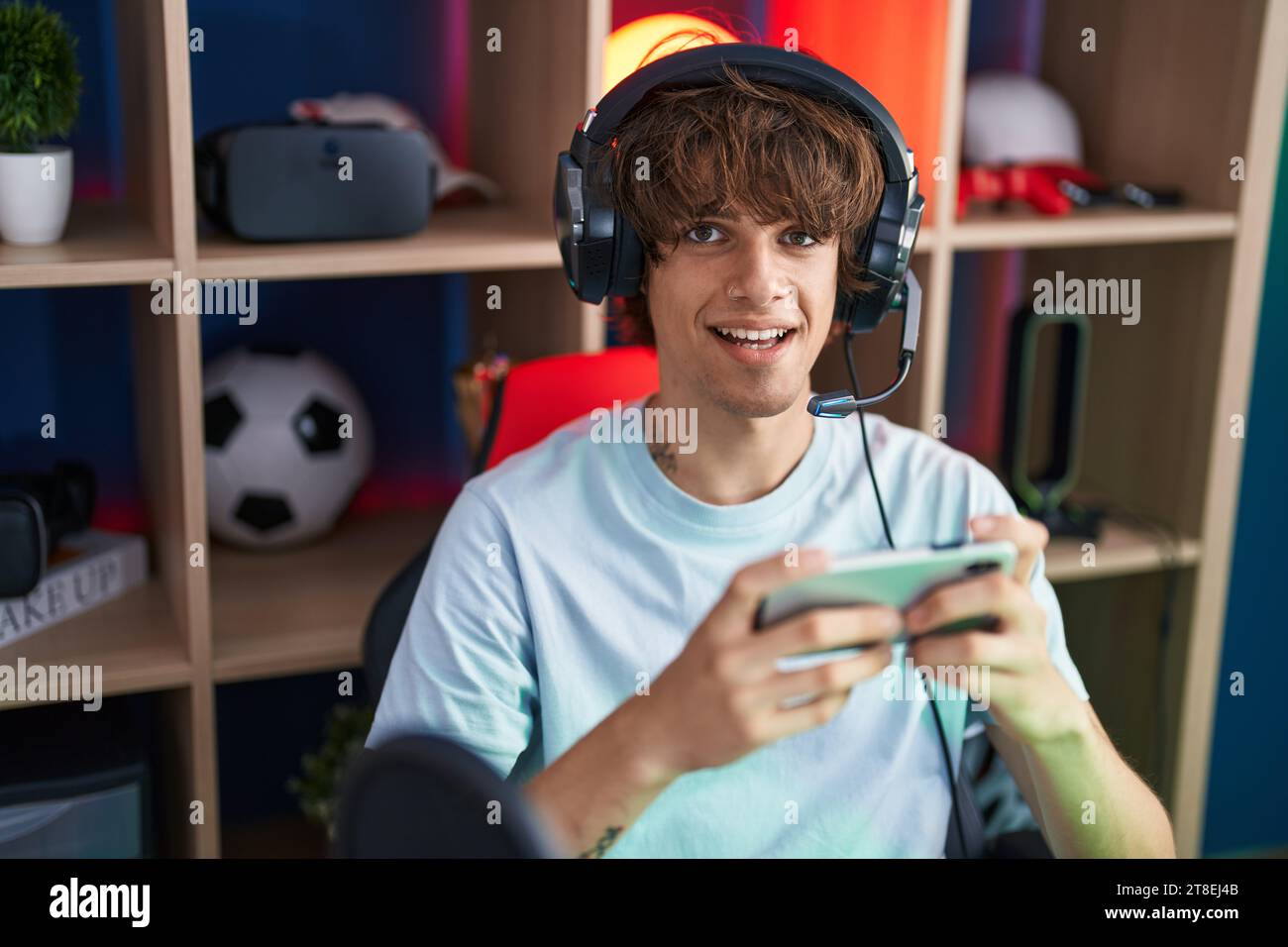 Young blond man streamer playing video game using smartphone at gaming ...