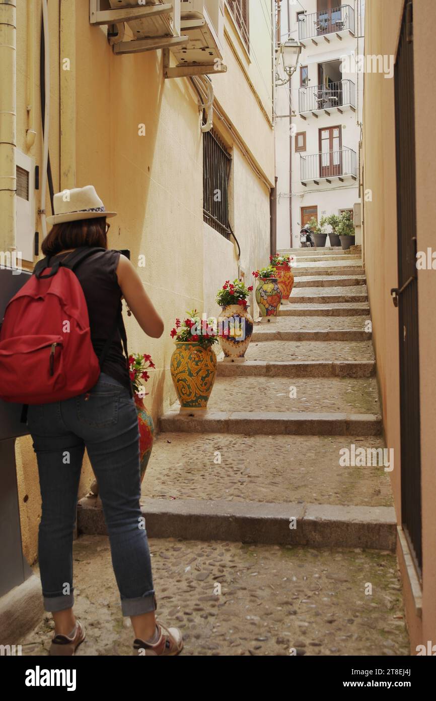 View of an alley with steps and colorful flower pots in Cefalu, Sicily ...