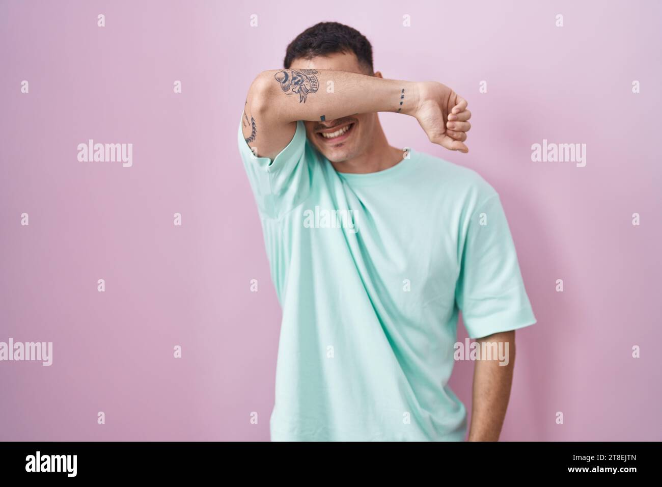 Handsome hispanic man standing over pink background covering eyes with ...