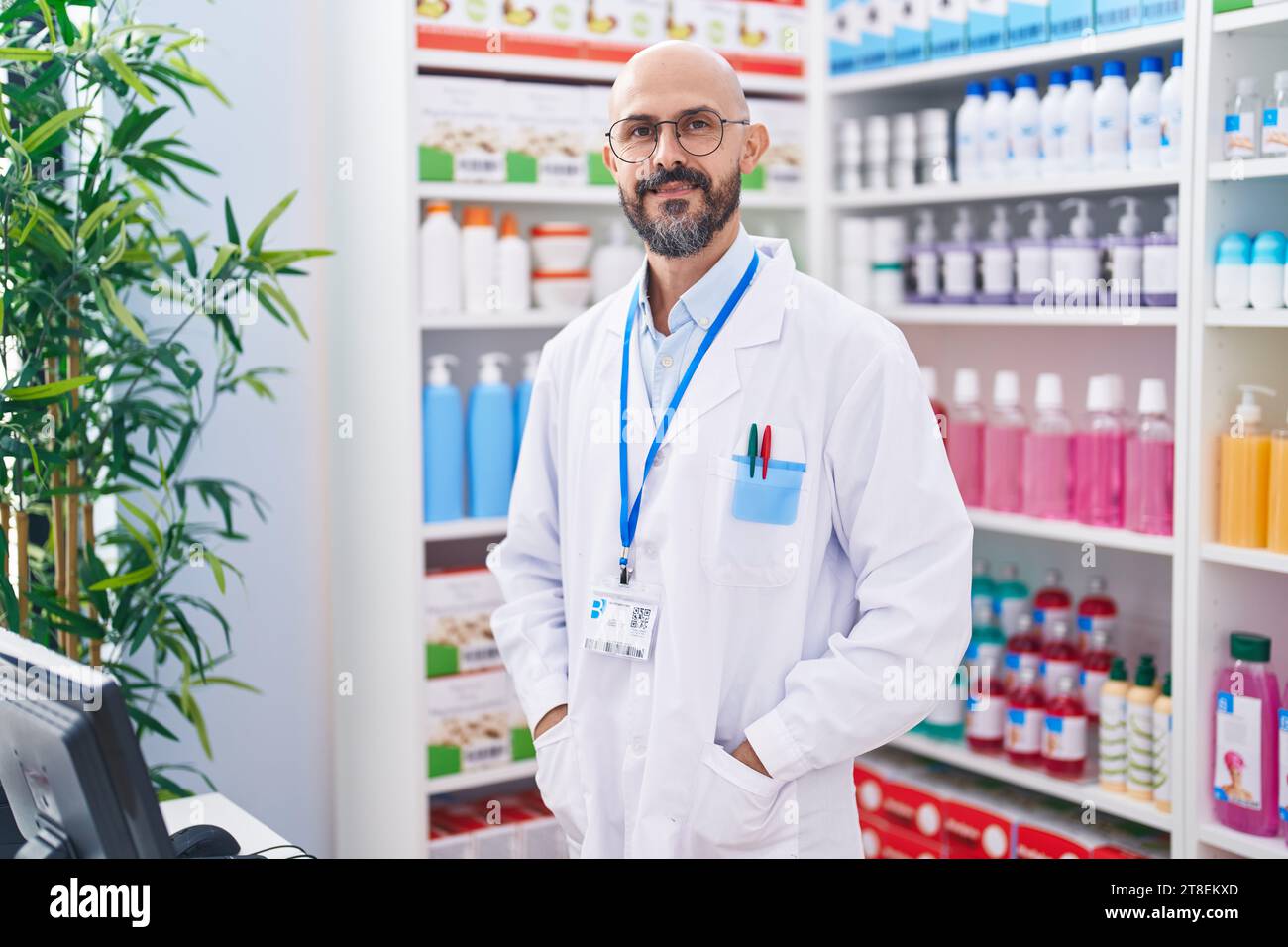 Young bald man pharmacist smiling confident standing at pharmacy Stock ...