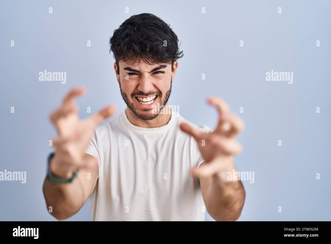 Hispanic man with beard standing over white background shouting ...