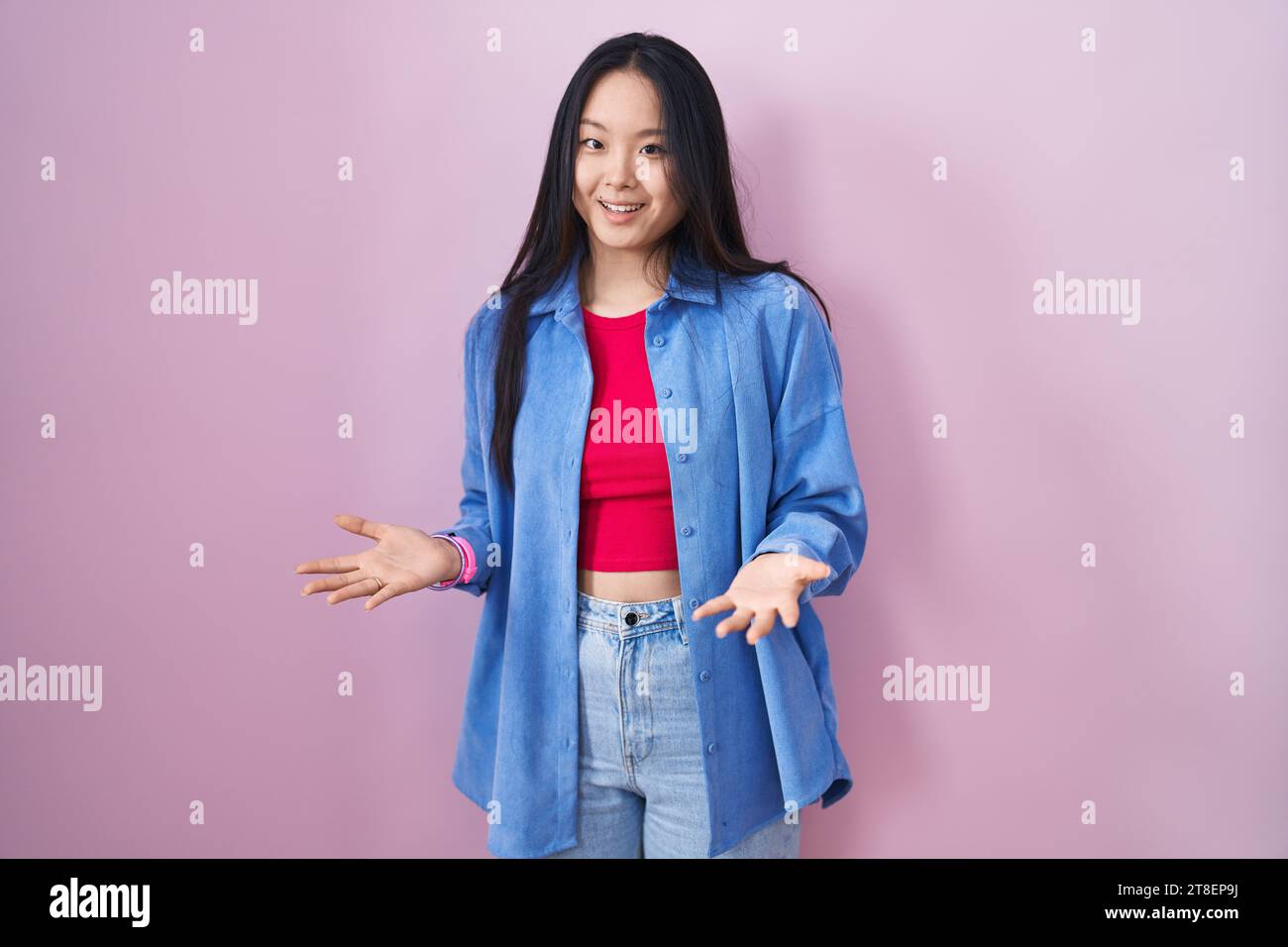 Young asian woman standing over pink background smiling cheerful with ...
