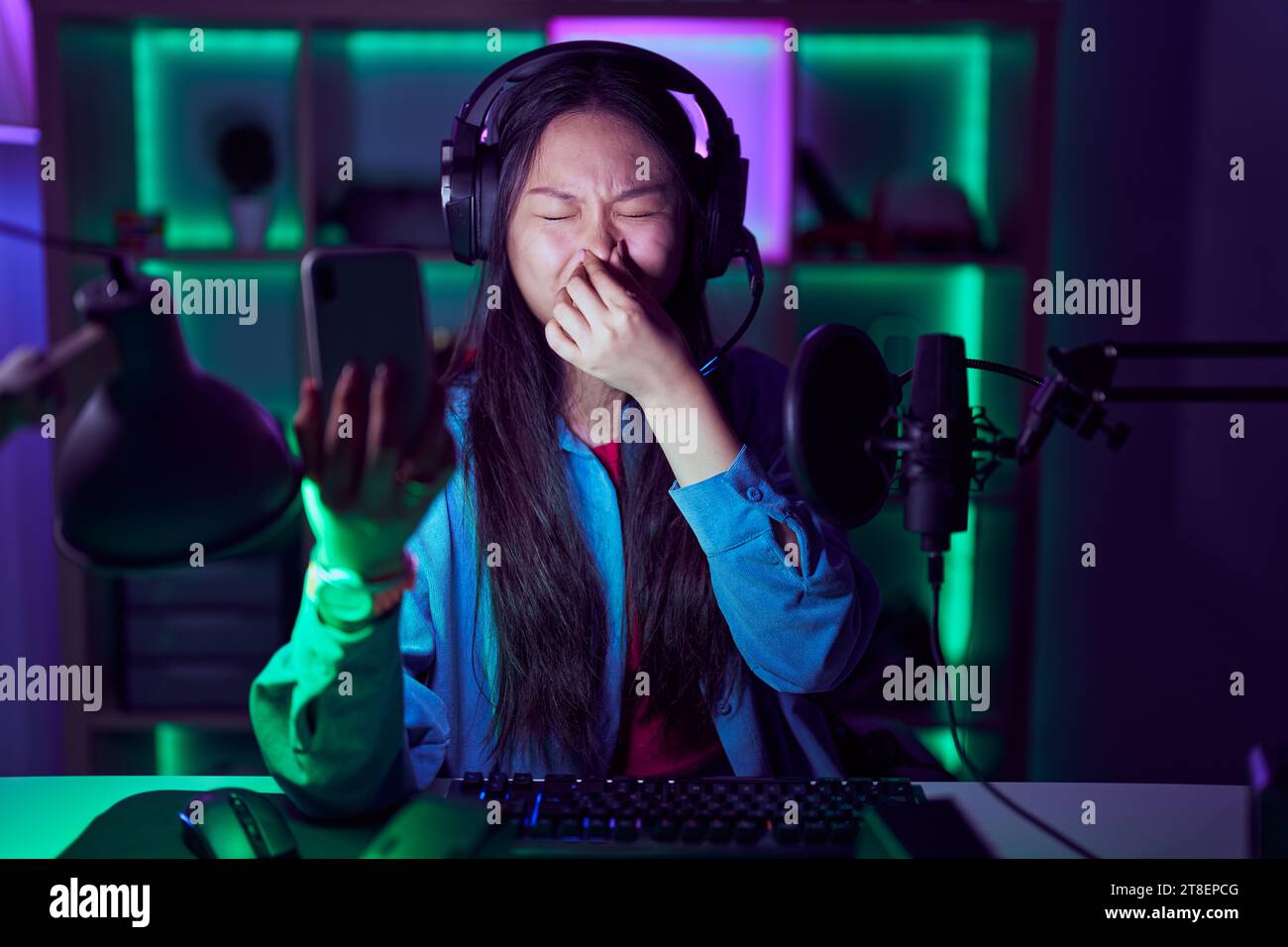 Young asian woman playing video games with smartphone smelling ...