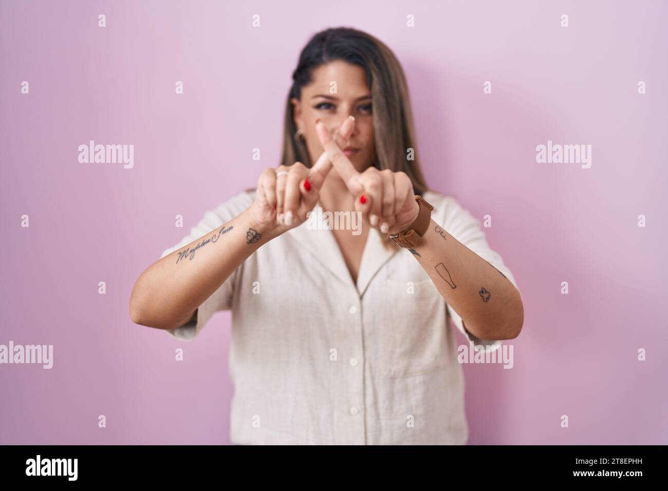 Blonde woman standing over pink background rejection expression ...