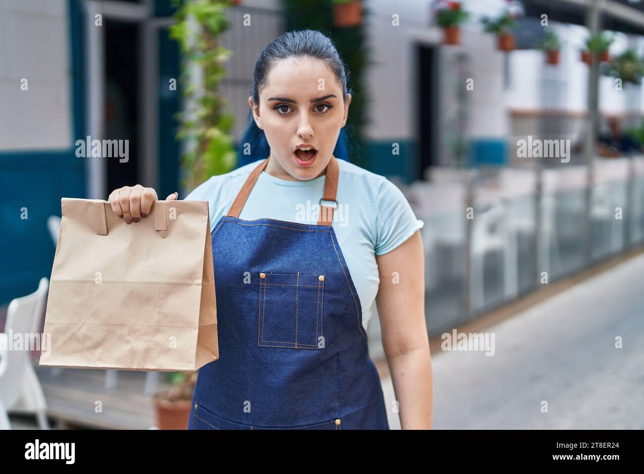 Young girl with blue hair wearing professional waitress apron holding ...