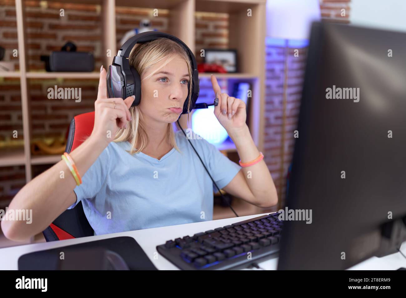 Young caucasian woman playing video games wearing headphones pointing ...