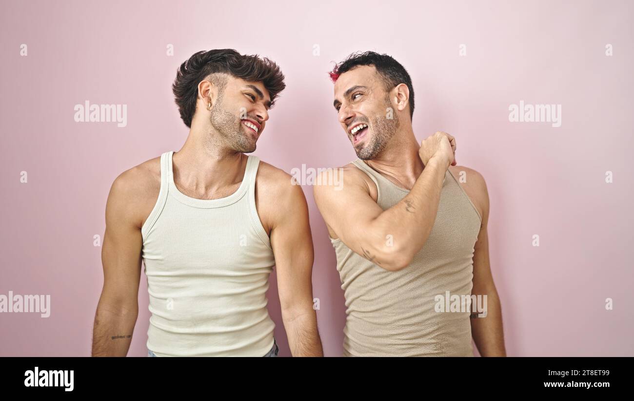 Two men couple smiling confident standing together over isolated pink ...