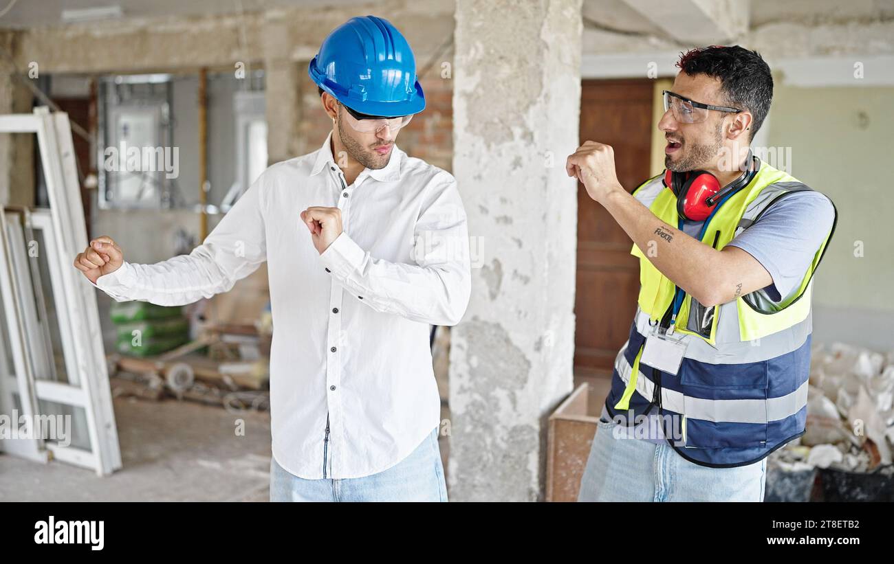 Two men builder and architect smiling confident dancing at construction ...