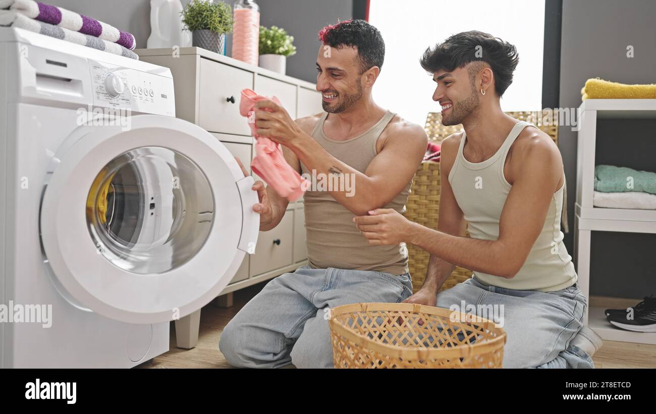 Two men couple smiling confident washing clothes at laundry room Stock ...
