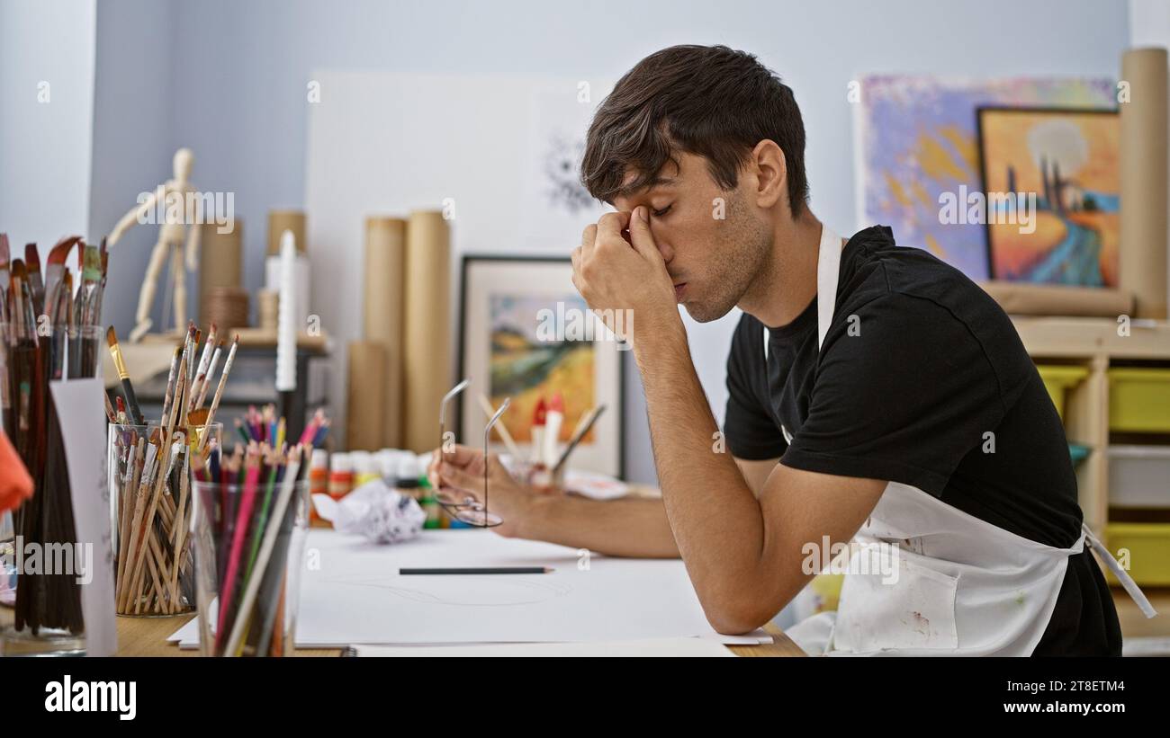 Stressed out young hispanic artist taking off glasses, feeling ...