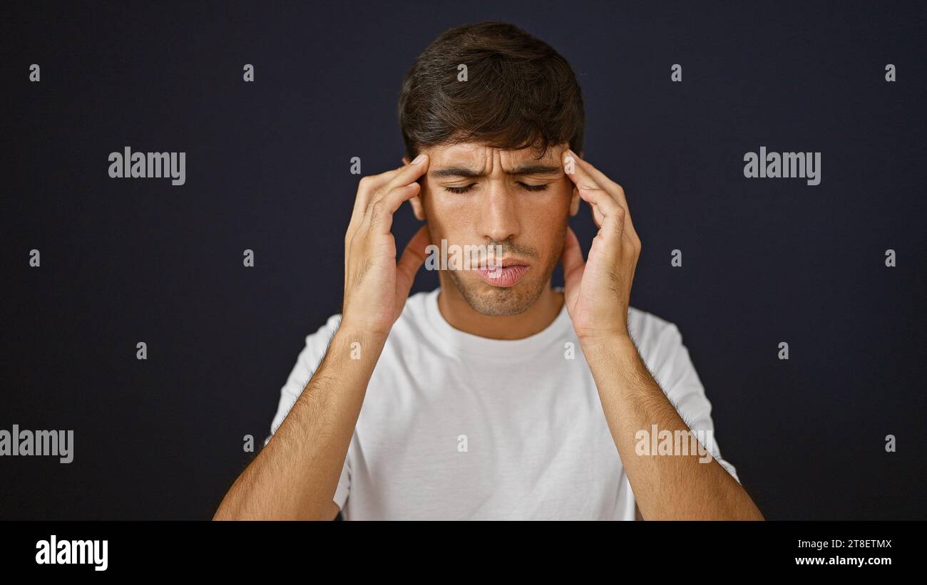 Frustrated young hispanic man, standing alone against an isolated black ...