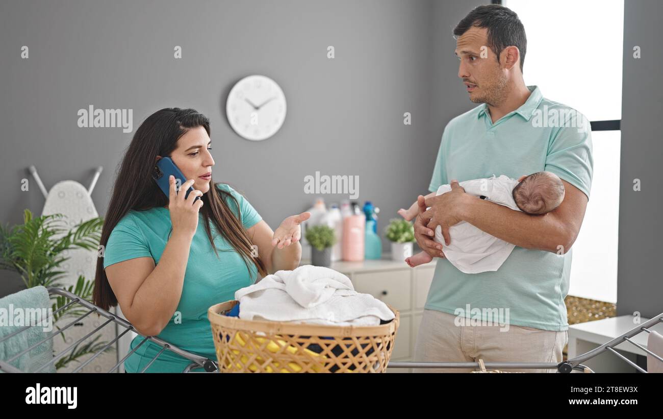 Family of three hanging clothes on clothesline using smartphone at ...