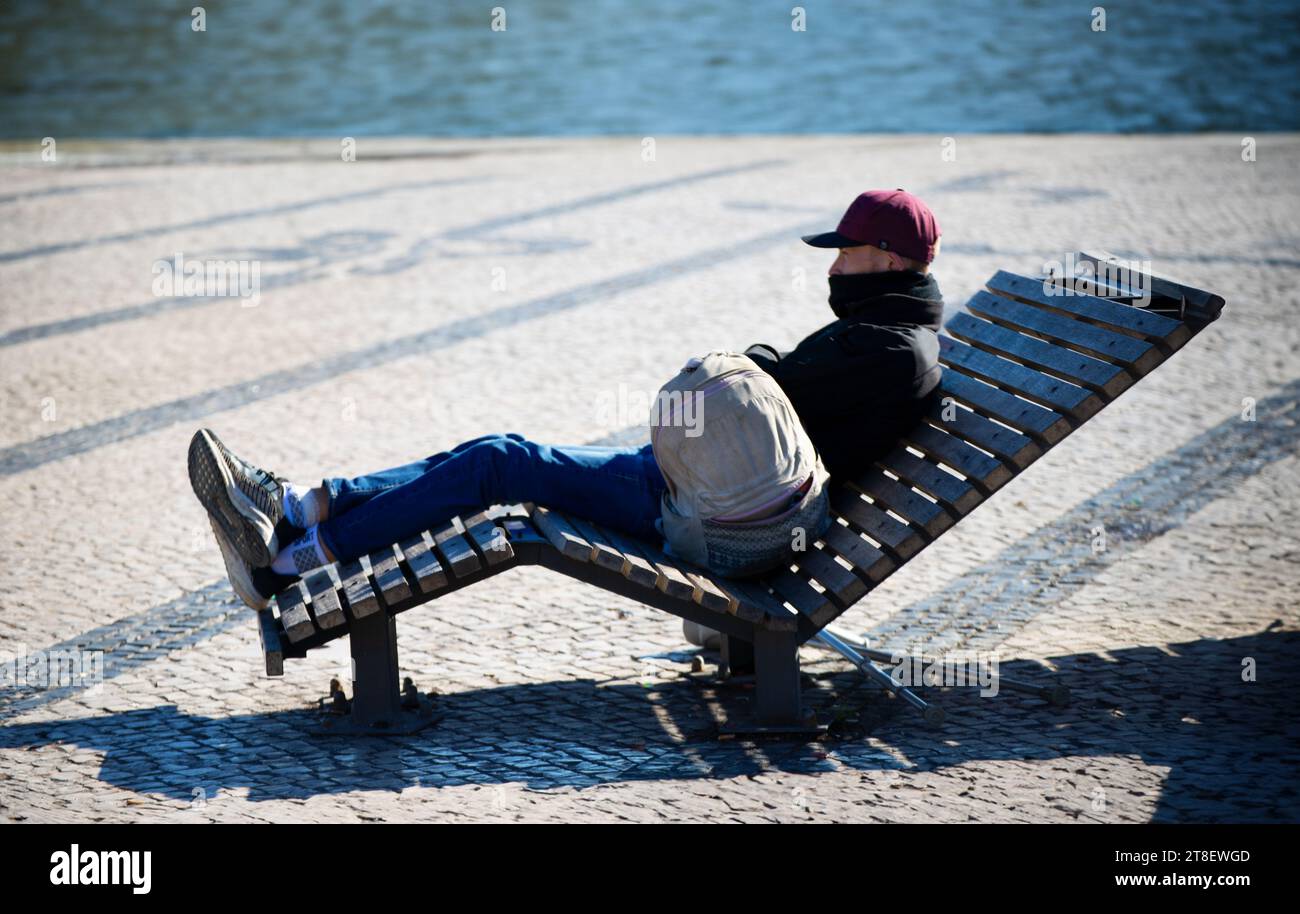 Homeless man sitting on a bench near the river in winter Stock Photo ...