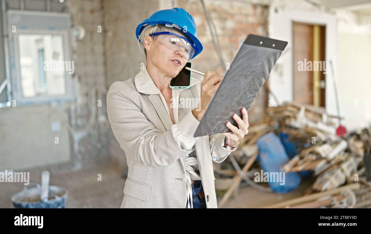 Middle age blonde woman architect talking on smartphone writing on ...