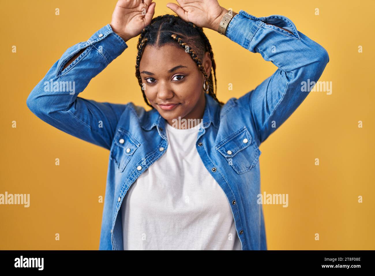 African american woman with braids standing over yellow background ...