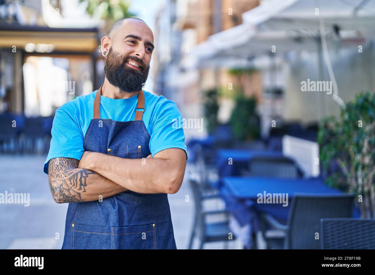 Young bald man waiter smiling confident standing with arms crossed ...