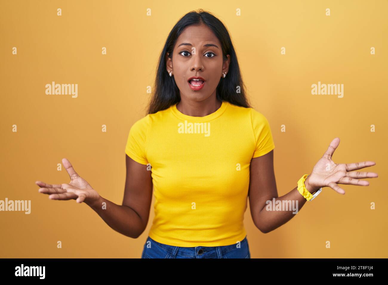 Young indian woman standing over yellow background smiling cheerful ...