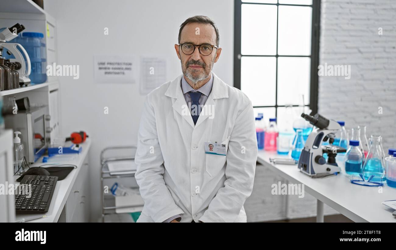 Serious-faced, middle-aged scientist with grey hair, sitting amid the ...