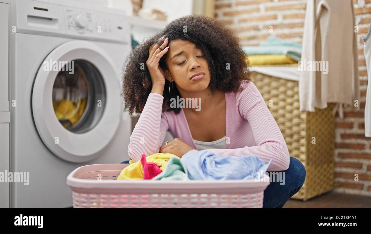 African american woman washing clothes looking upset at laundry room ...
