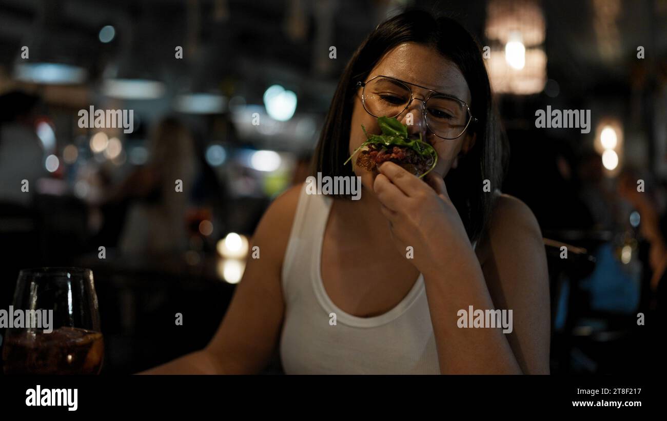 Young beautiful hispanic woman eating delicious italian food at the ...