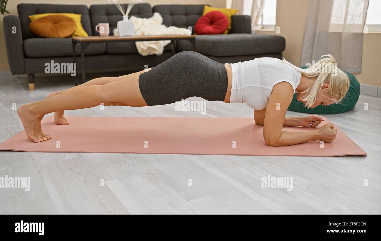 Attractive blonde woman diving into a hardcore core exercise training at home, getting her ...