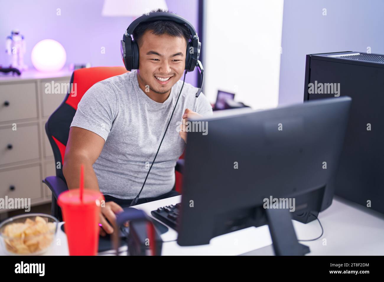 Young chinese man streamer playing video game using computer at gaming ...