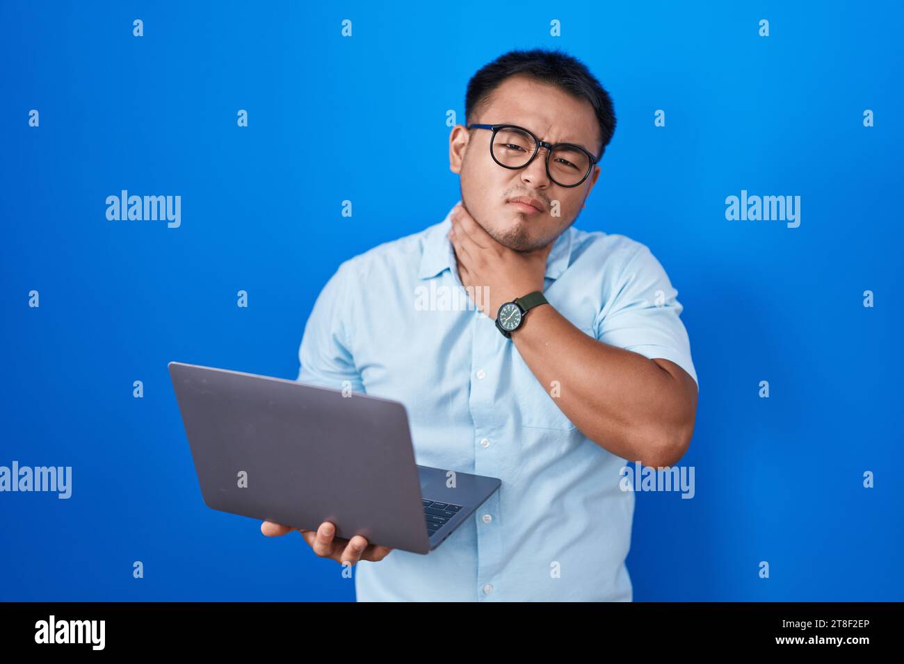 Chinese young man using computer laptop touching painful neck, sore ...